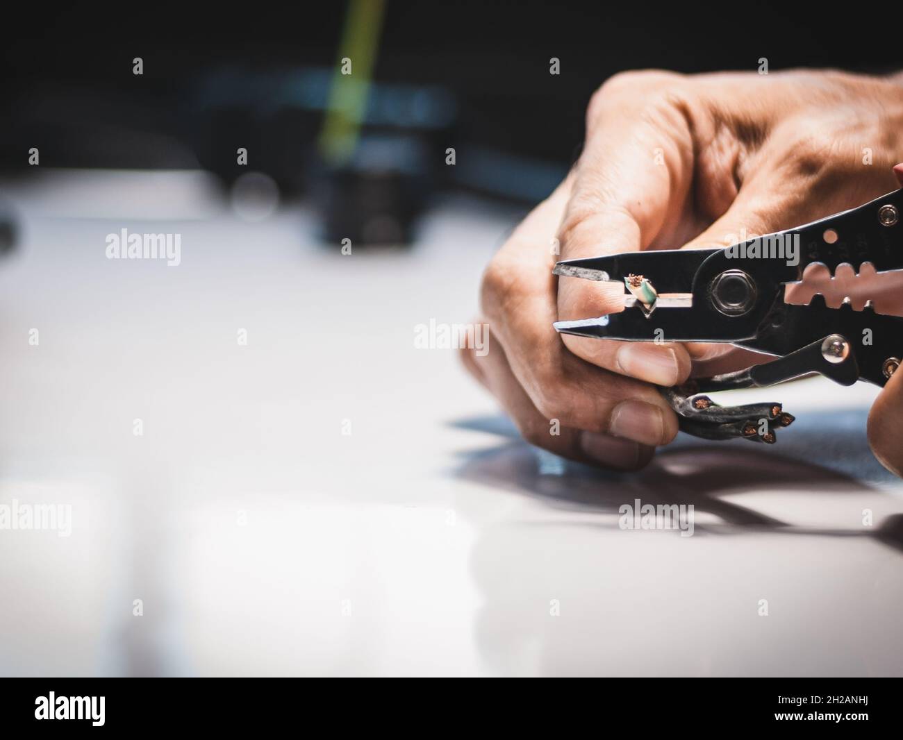 Closeup at the hand of an electrician is using electrical stripping ...