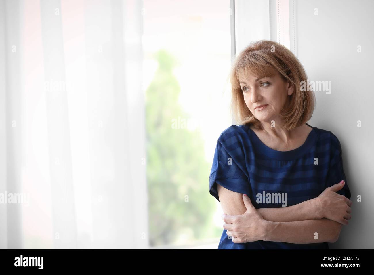 Senior woman suffering from depression near window Stock Photo - Alamy