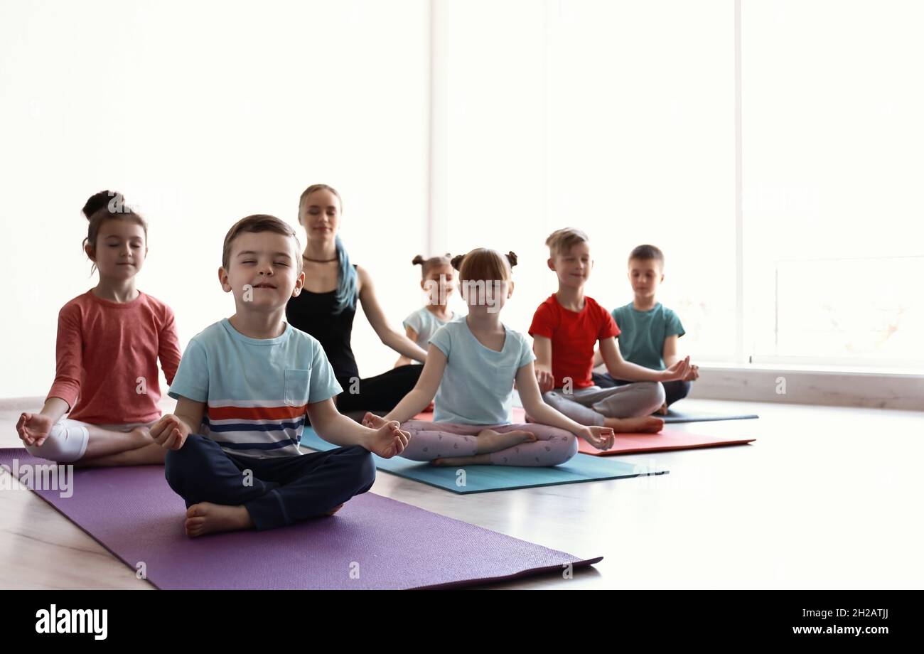 Little children and their teacher practicing yoga in gym Stock Photo ...