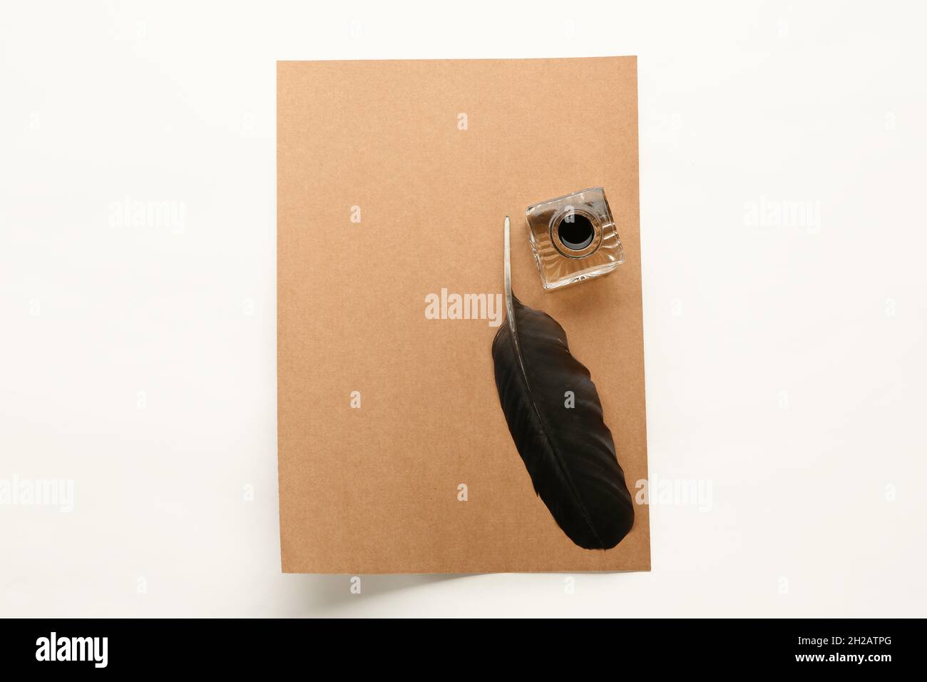 Feather pen, inkwell and sheet of paper on white background, top view ...