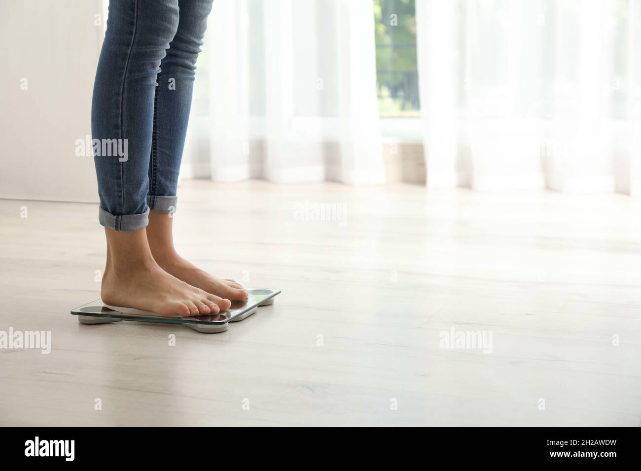Woman measuring her weight using scales on wooden floor. Healthy diet ...