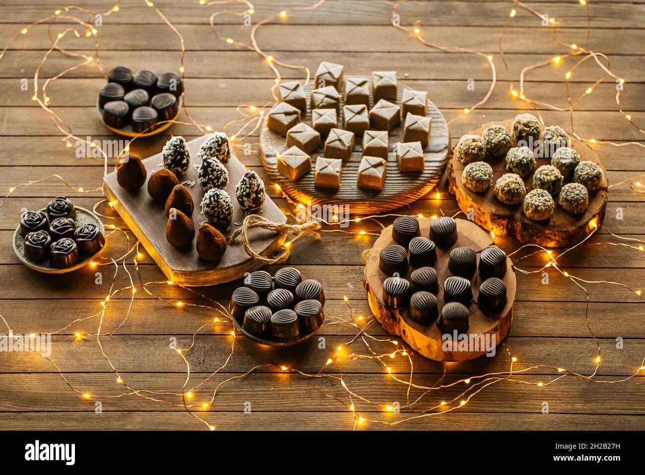 Assorted chocolates on wooden table with garland Stock Photo - Alamy