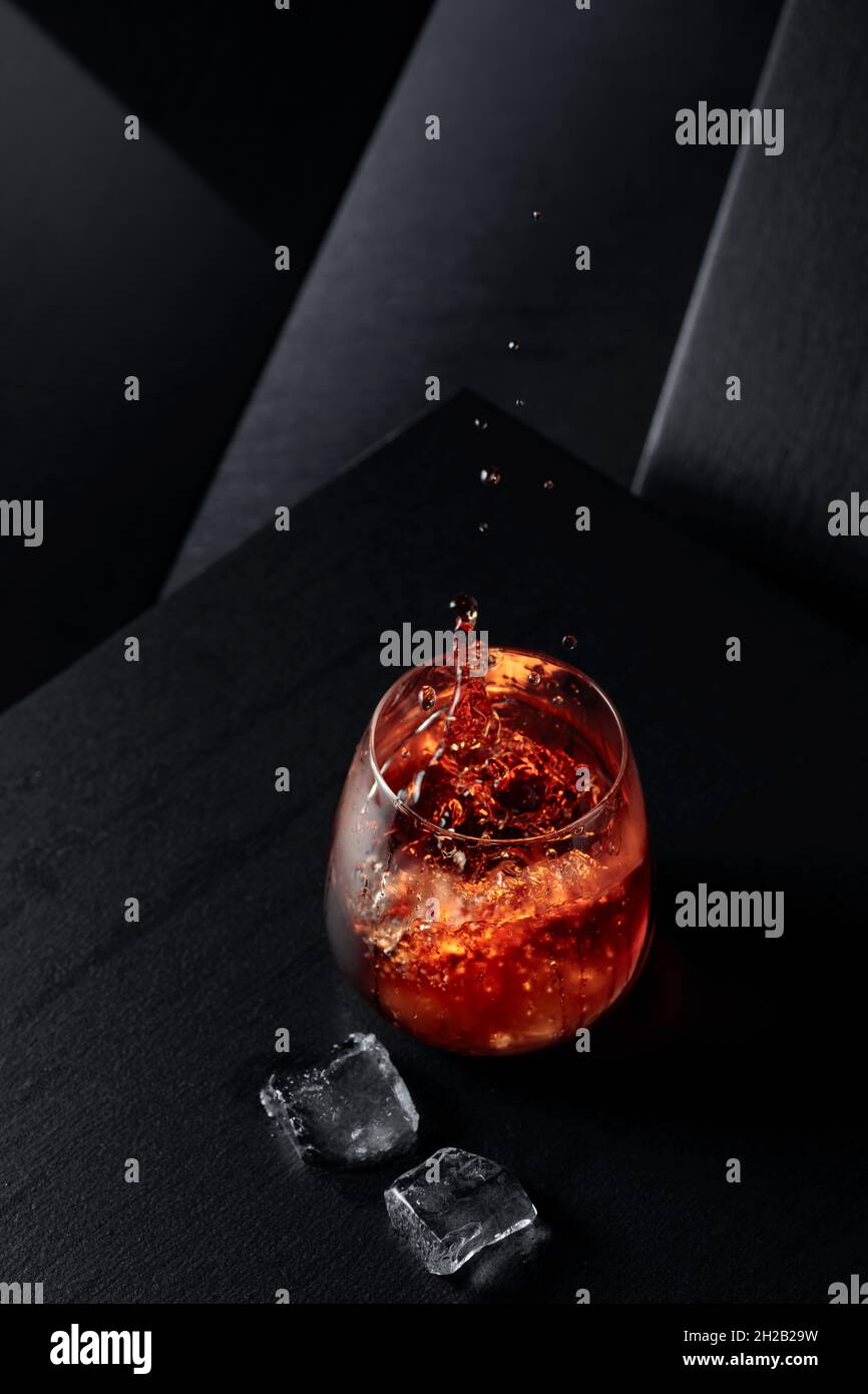 Ice cubes fall into a glass of whiskey creating splashes Stock Photo - Alamy