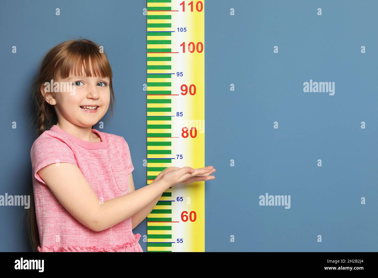 Little girl measuring her height on color background Stock Photo - Alamy