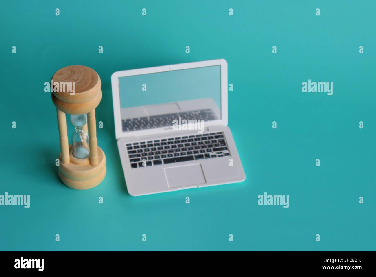 Selective focus image of hourglass and laptop on green background ...