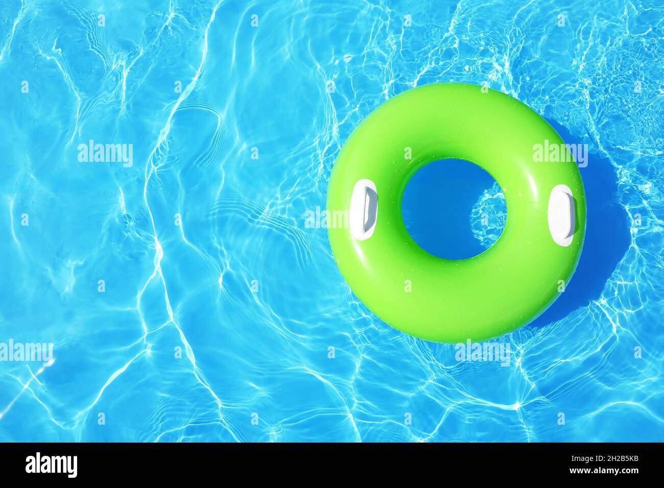 Inflatable ring floating in swimming pool on sunny day, top view with ...
