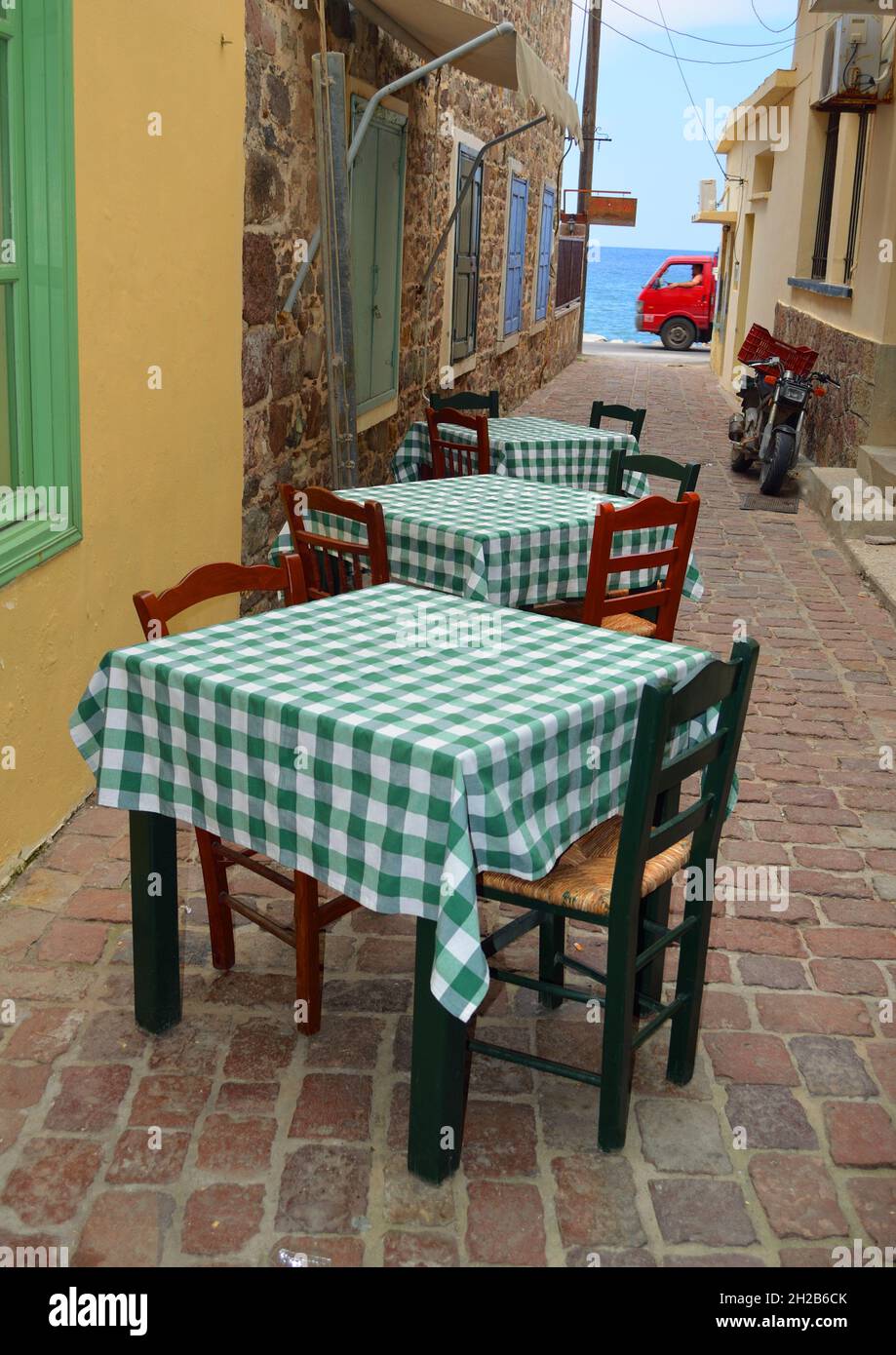 Three Cafe tables in alleyway leading to the sea Stock Photo - Alamy