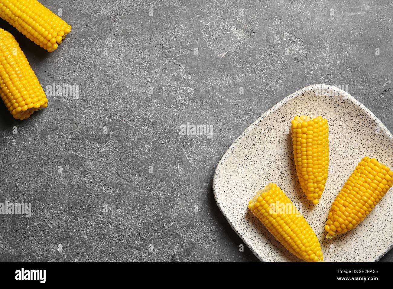 Flat lay composition with corn cobs on grey background. Space for text ...