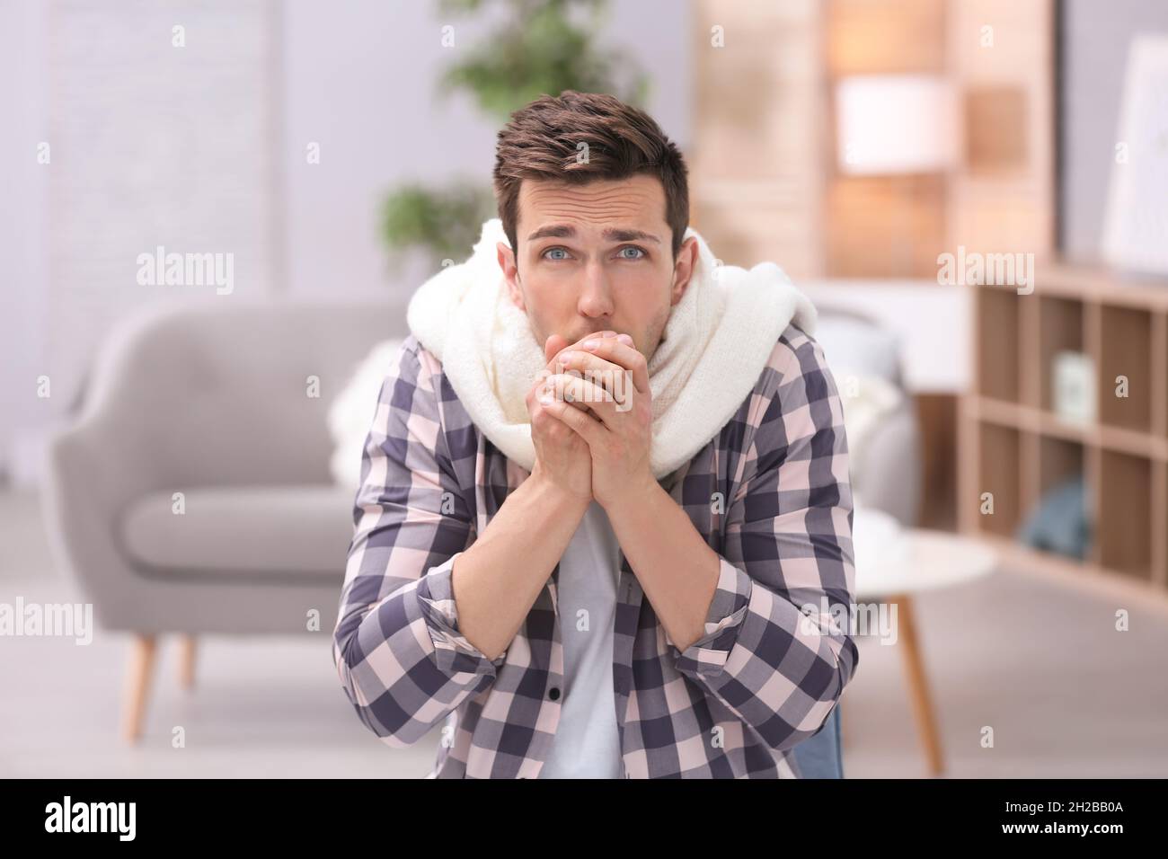 Sad young man suffering from cold on blurred background Stock Photo - Alamy