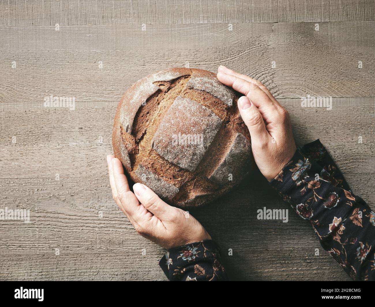 freshly baked artisan bread in human hands on old wooden table, top ...