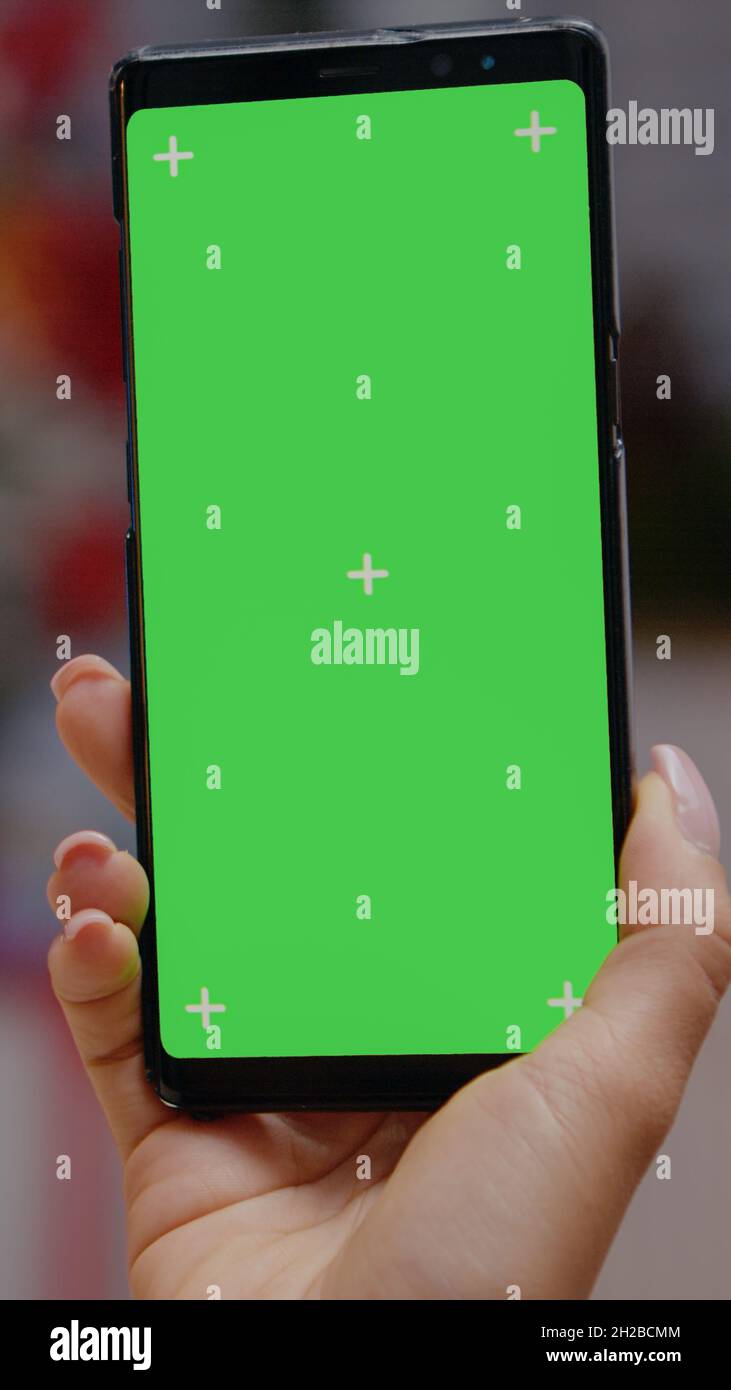 Close up of hand vertically holding smartphone with green screen. Woman ...