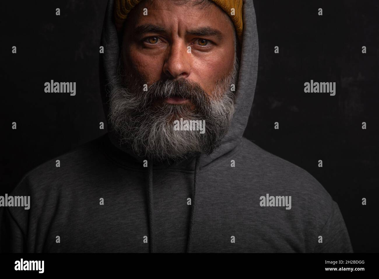 Close up of a mature man with hood and dirty sad eyes looking at the ...