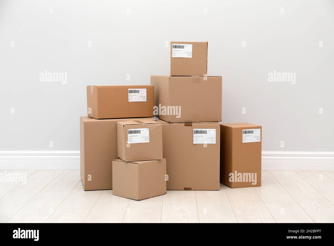 Stacked parcel boxes on floor against light wall Stock Photo - Alamy