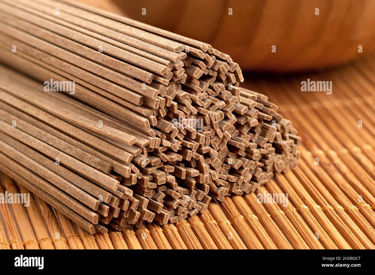 Stack of dry soba noodles on a bamboo matt next to a bamboo bowl Stock ...