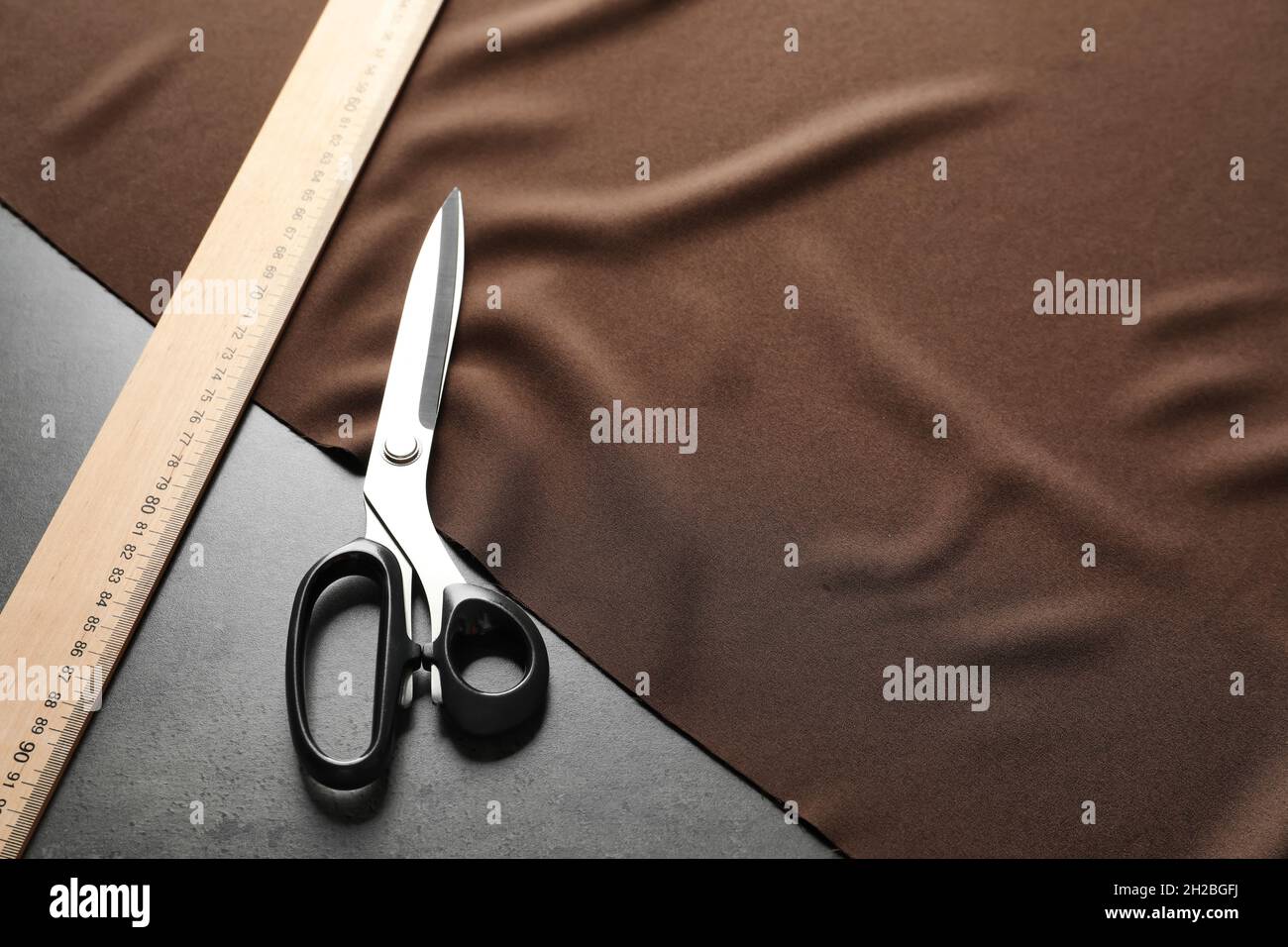 Scissors, ruler and fabric on grey background. Tailoring equipment ...