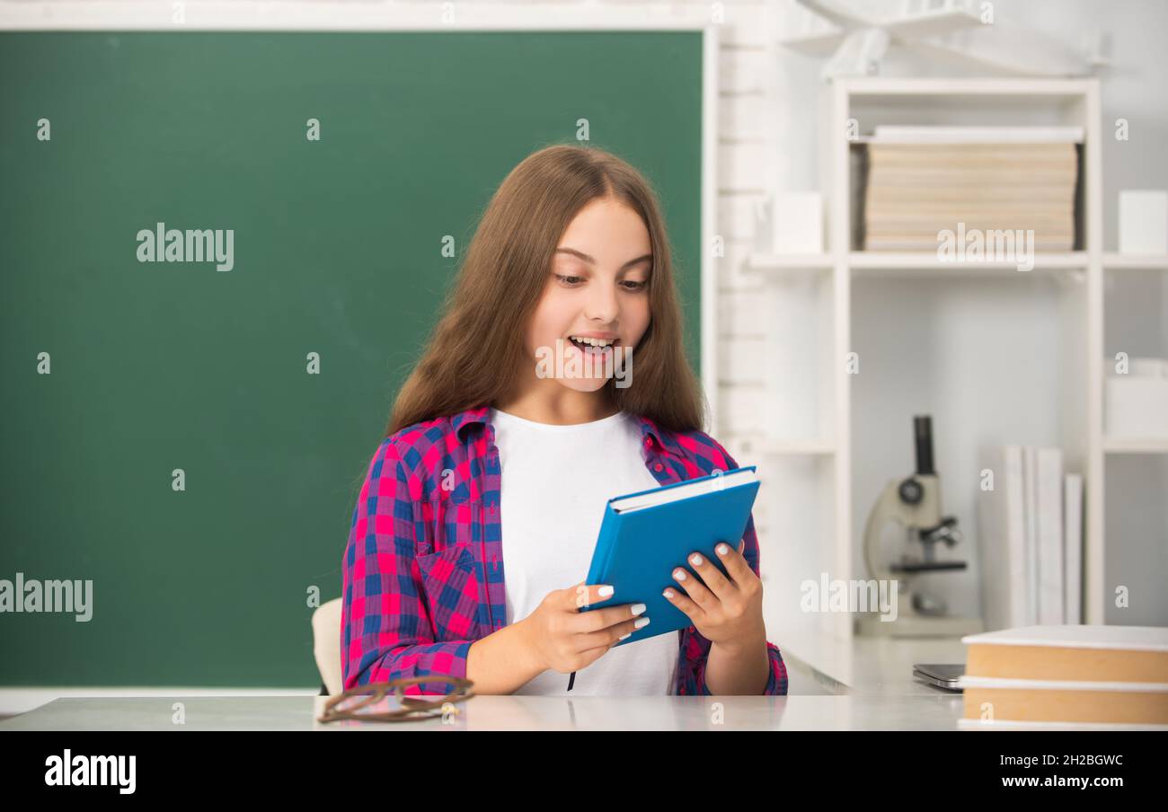 amazed kid sitting with copybook in classroom at blackboard, education ...