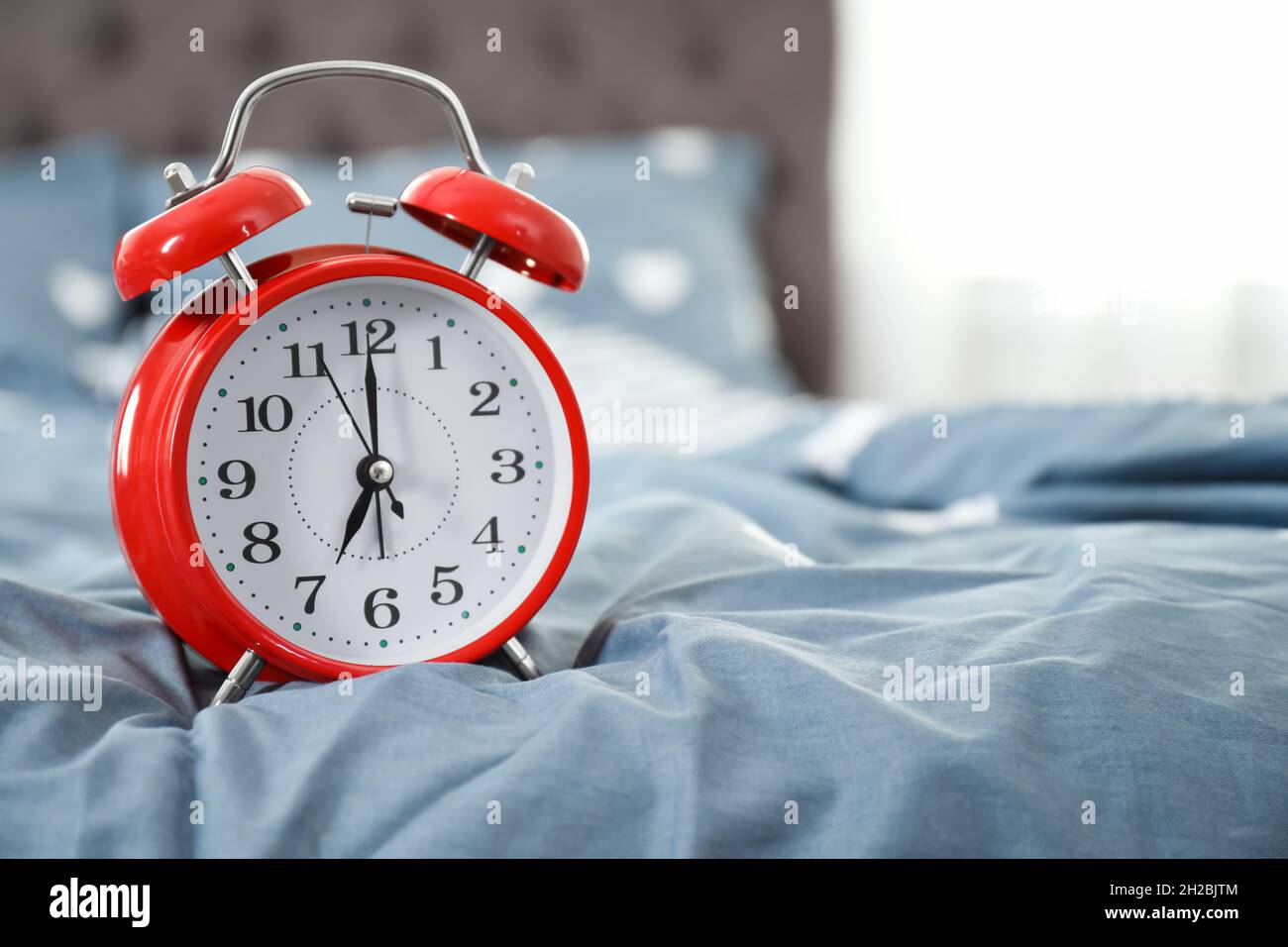Analog alarm clock on bed. Time of day Stock Photo - Alamy