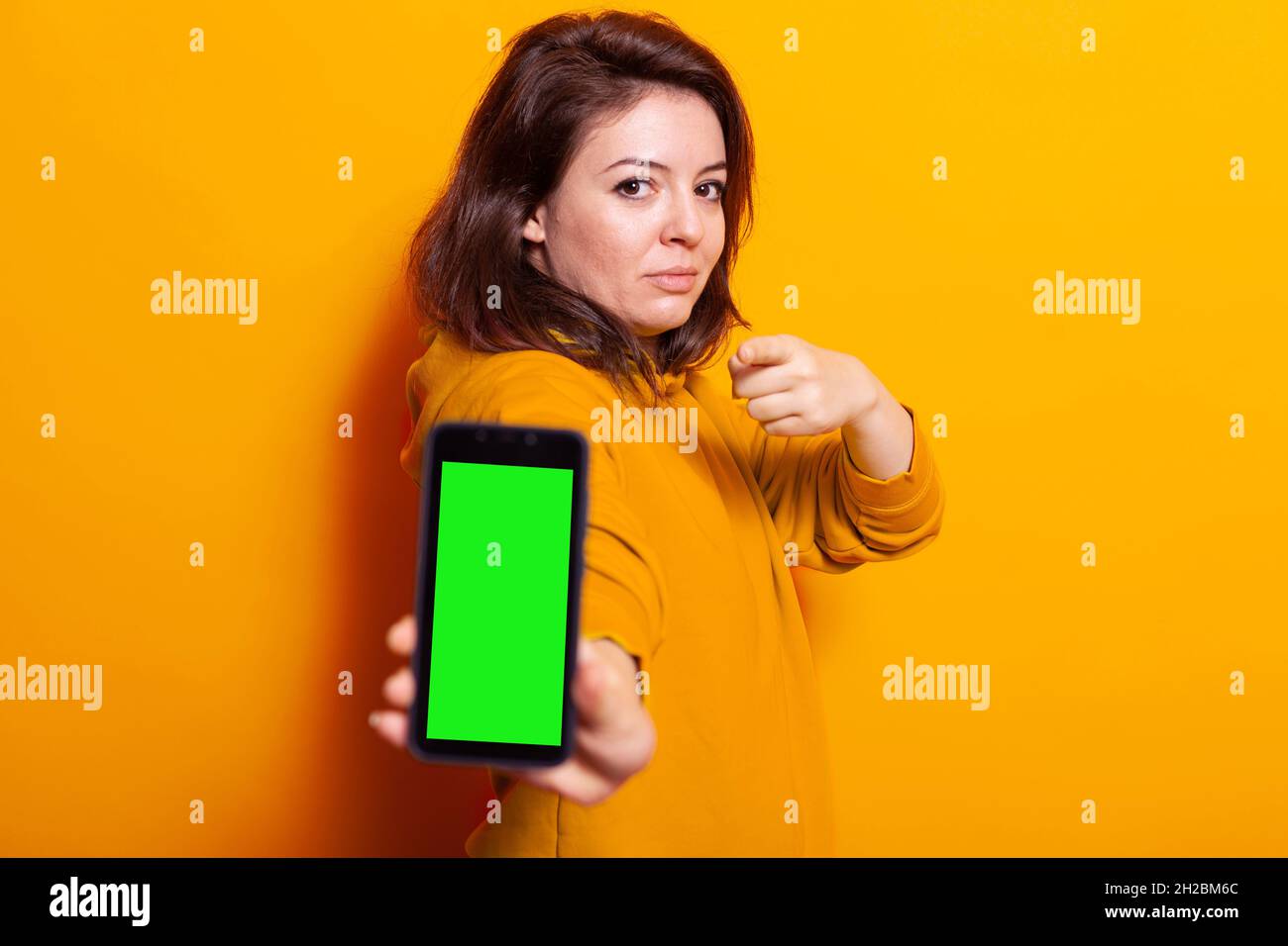 Woman showing mobile phone with vertical green screen at camera in ...