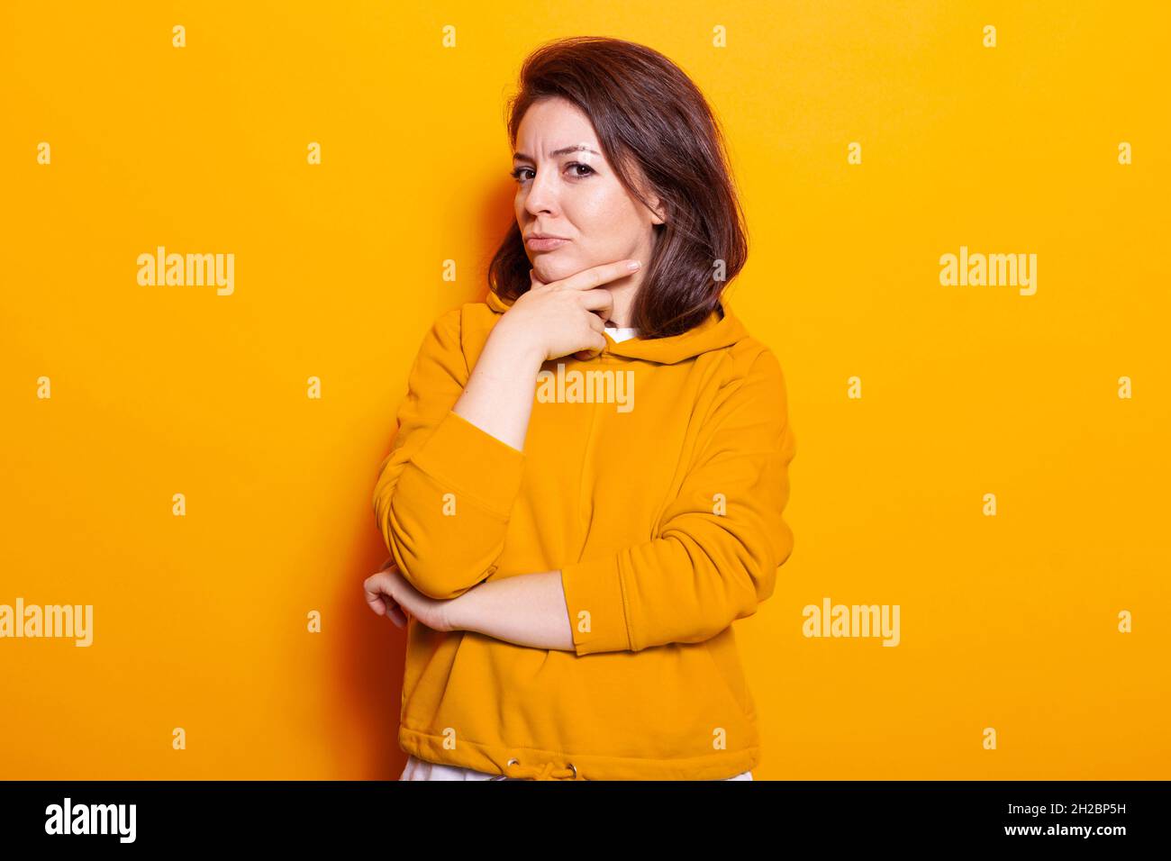 Caucasian woman doing thinking face with hand on chin at camera ...