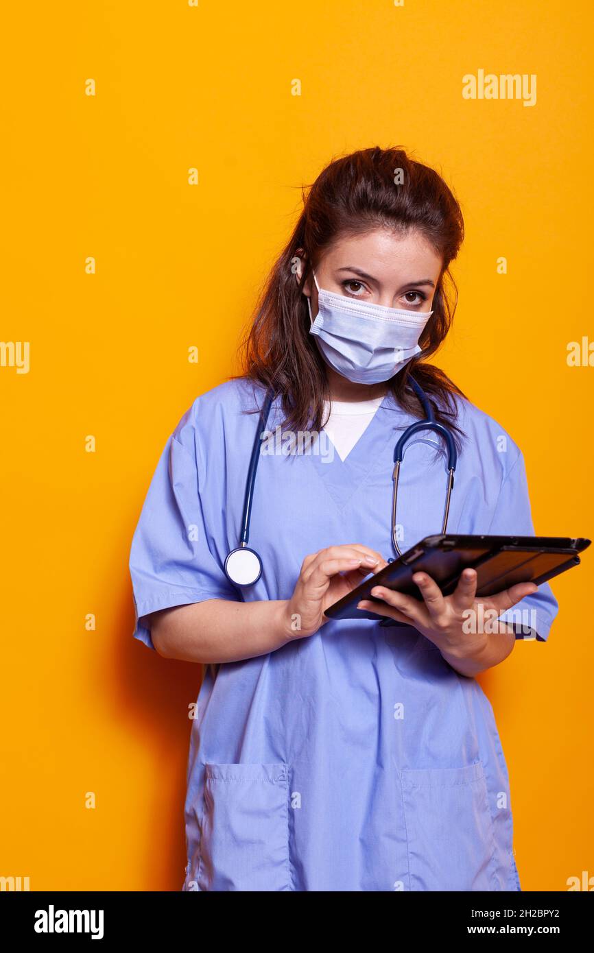 Medical assistant wearing face mask using digital device, having ...