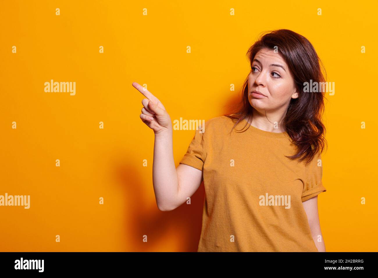 Caucasian person indicating finger at left side of studio while posing ...