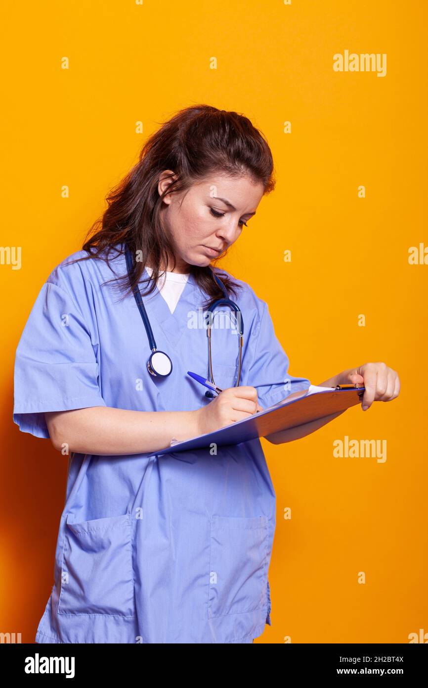 Woman nurse with uniform writing on clipboard papers, standing over ...