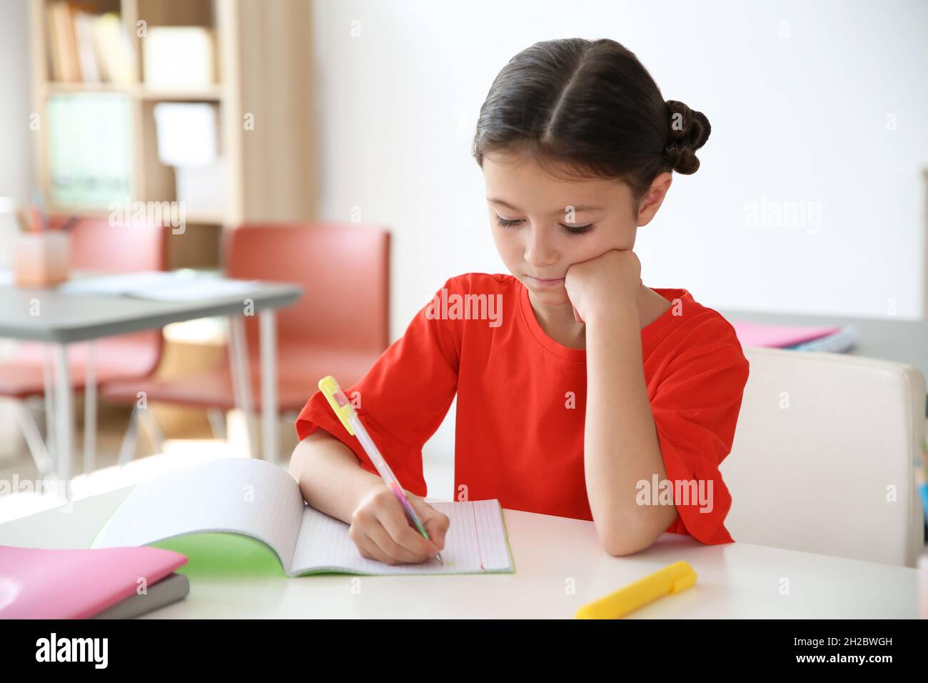 Cute little child doing assignment at desk in classroom. Elementary ...