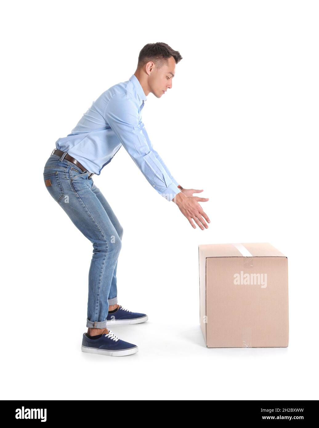 Full length portrait of young man lifting heavy cardboard box on white ...