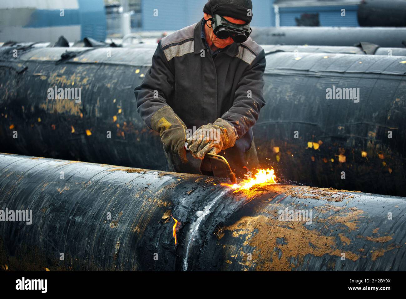 The welder cuts large metal pipes with ocetylene welding. A worker on ...