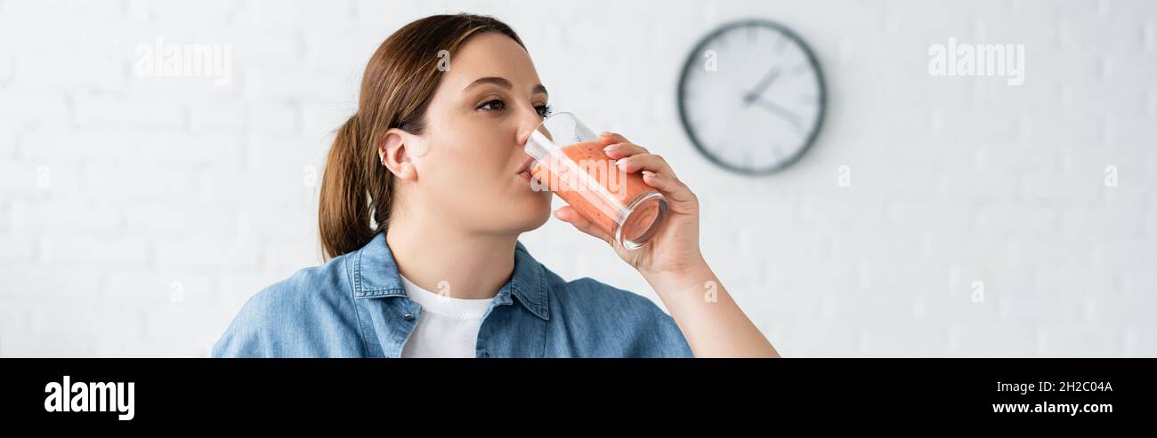 Plus size woman drinking fruit smoothie in kitchen, banner Stock Photo ...