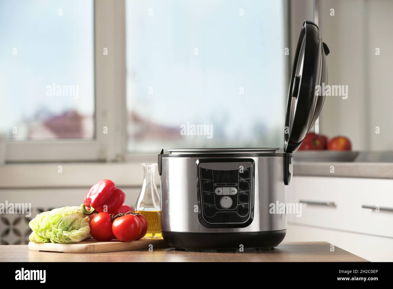 Modern multi cooker and products on table in kitchen. Space for text ...