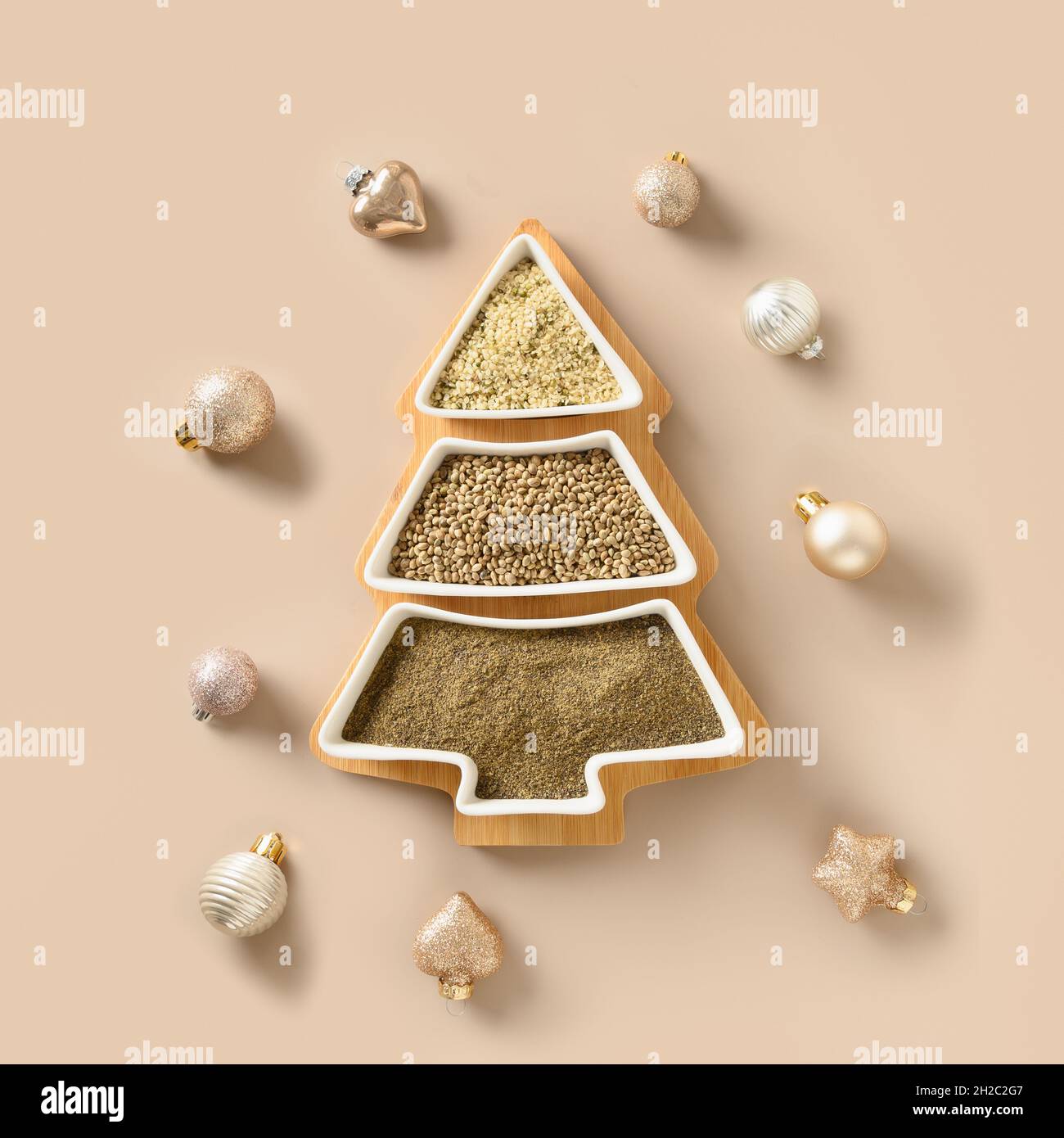 Hemp seeds, flour, kernels in plate shape of Christmas tree on pastel ...