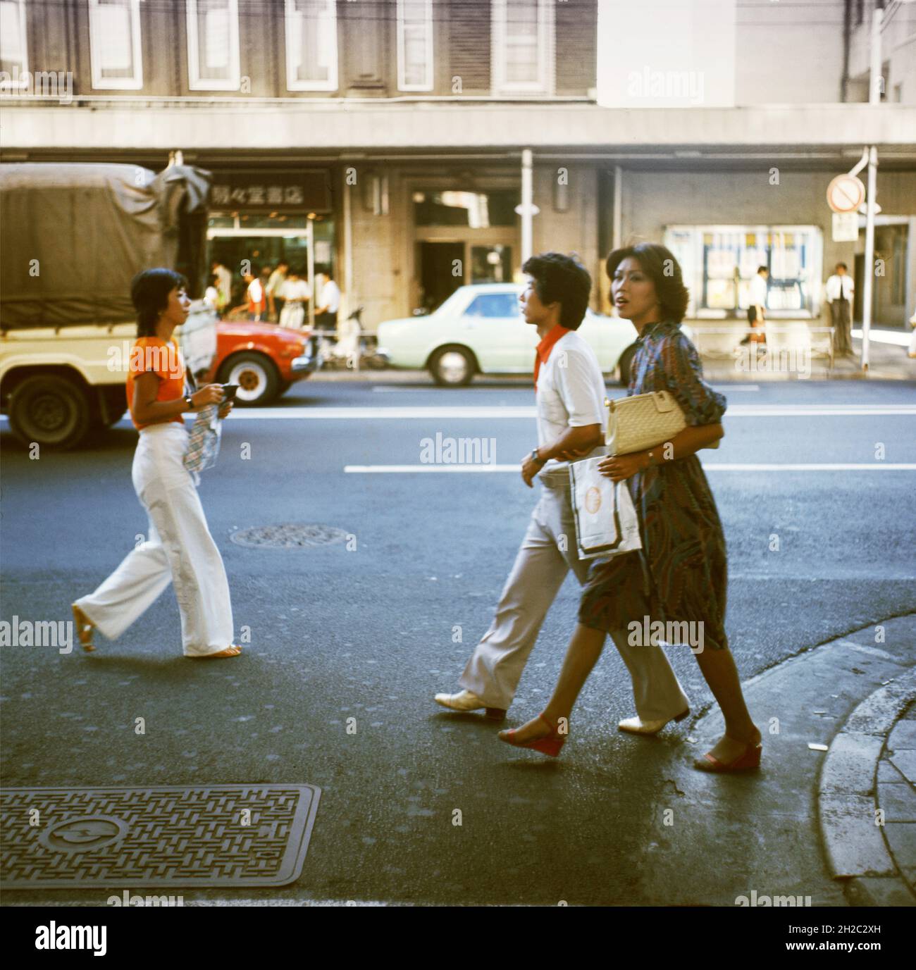 A couple of young people are walking down the street. Japan, 1970s ...