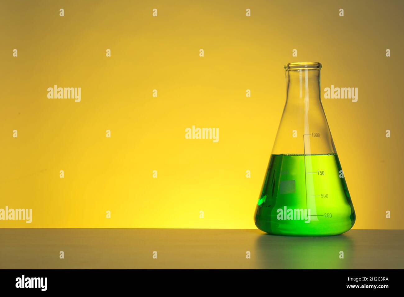 Conical flask with liquid on table against color background. Chemistry ...