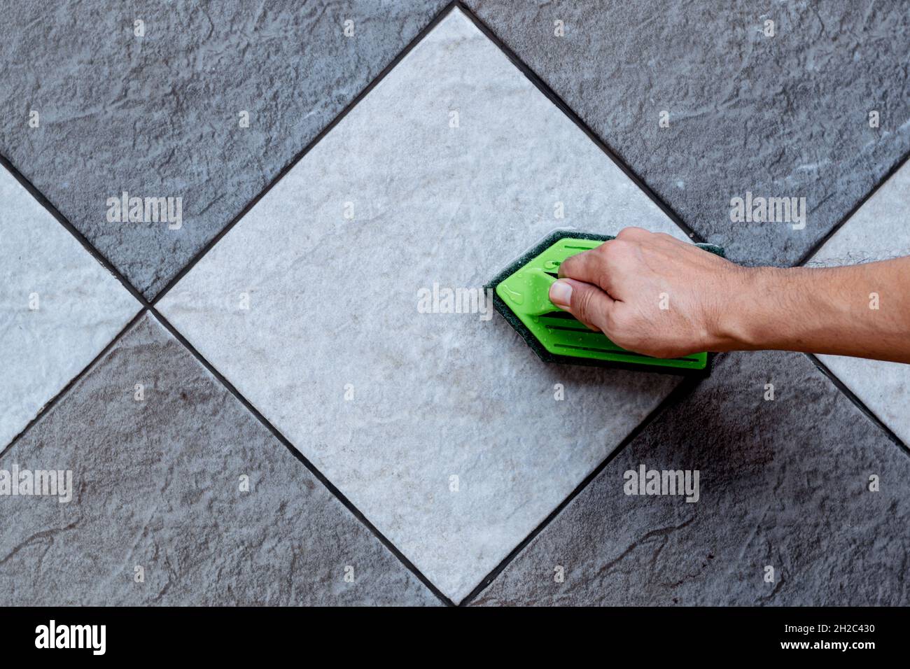 Top view of a human hand are using a green color plastic floor scrubber ...