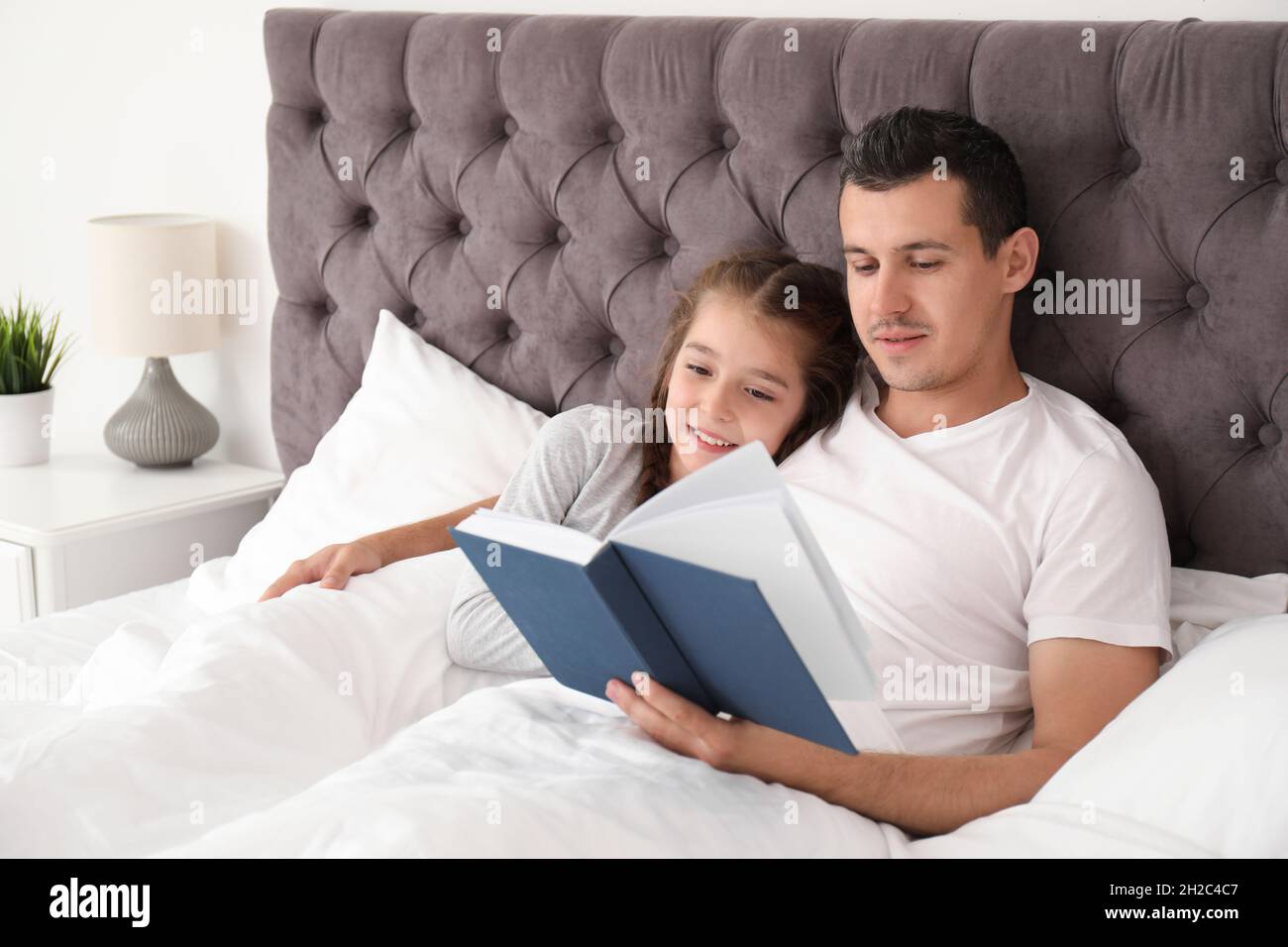 Father reading book with child in bedroom. Happy family Stock Photo - Alamy