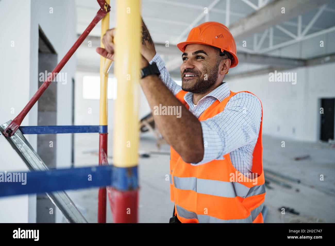Young handsome builder climbing on scaffolding at construction site ...
