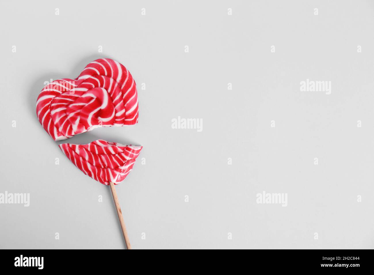 Broken heart shaped lollipop on white background, top view. Space for ...