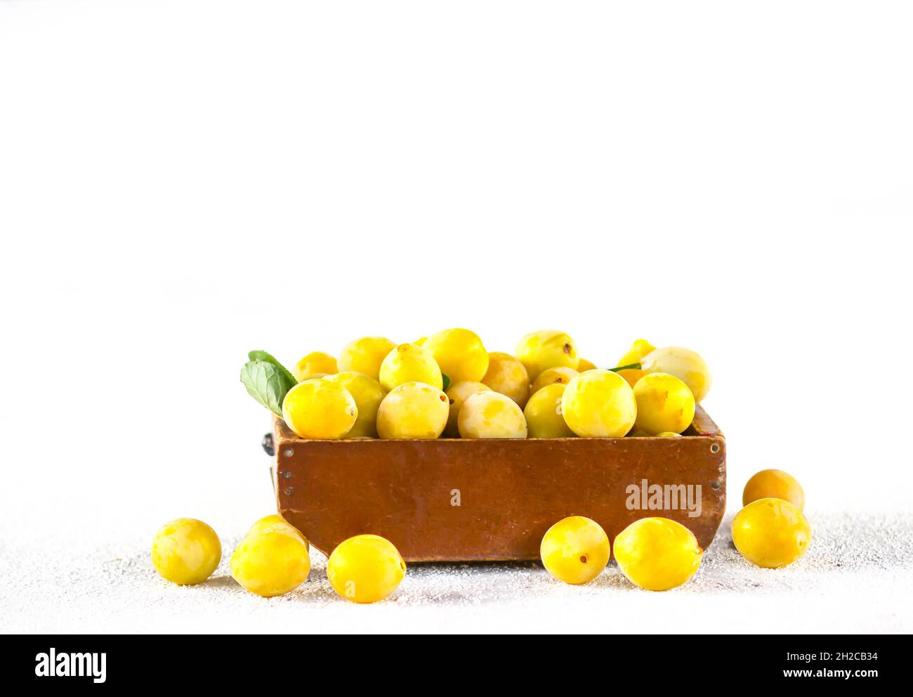 Fresh yellow plums. Ripe fruits in a wooden box on white background ...