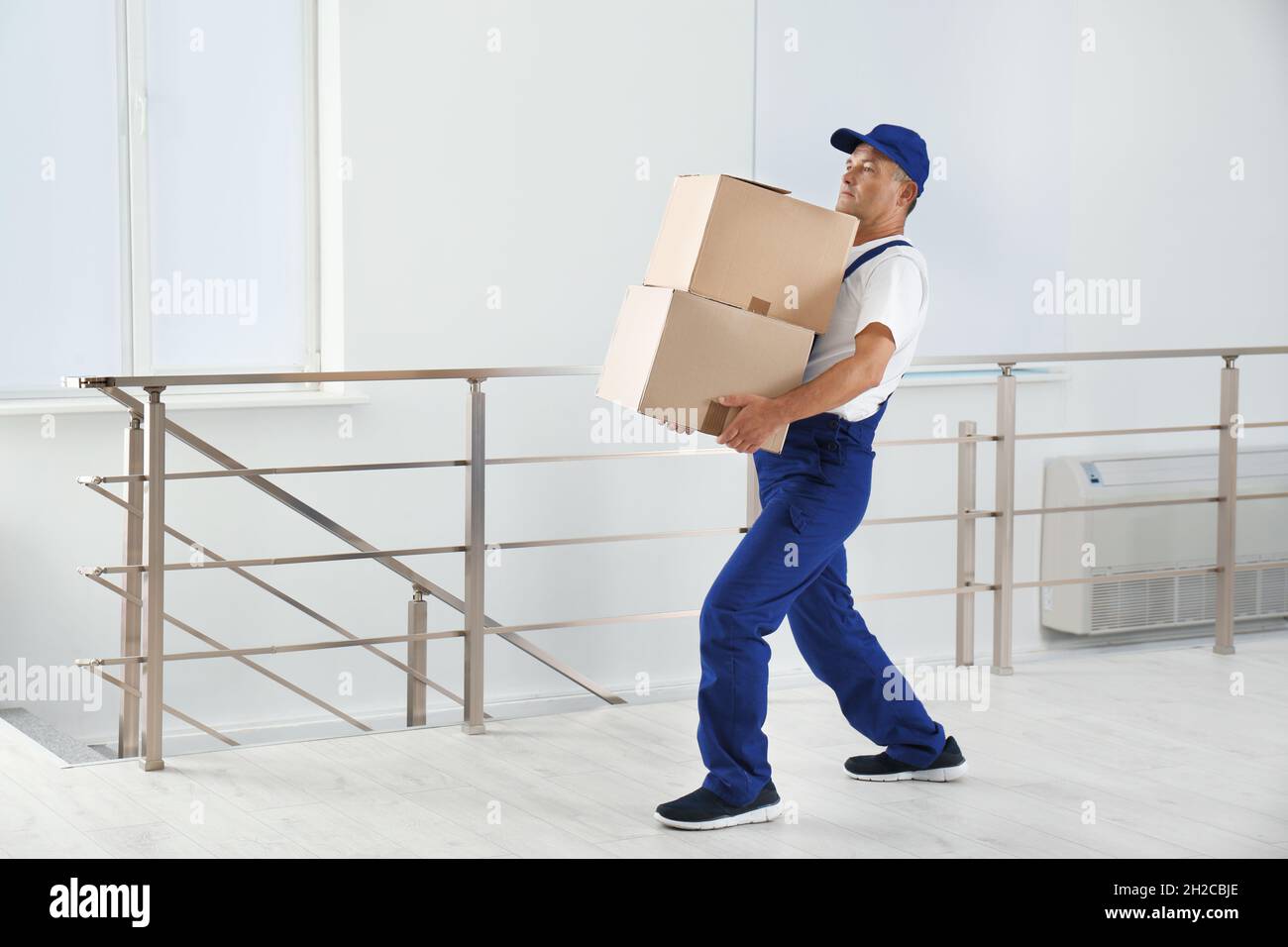 Man in uniform carrying carton boxes indoors. Posture concept Stock ...