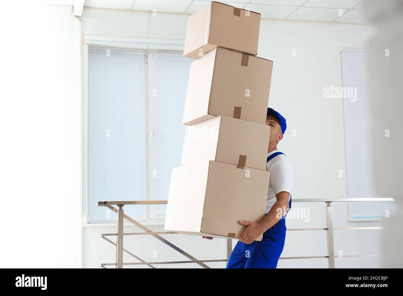 Man in uniform carrying carton boxes indoors. Posture concept Stock ...