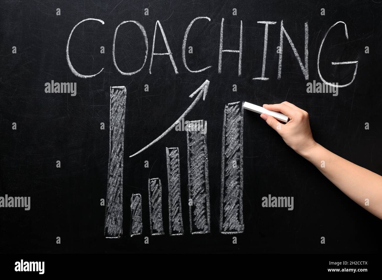 Woman drawing bar chart with word COACHING on chalkboard. Business ...