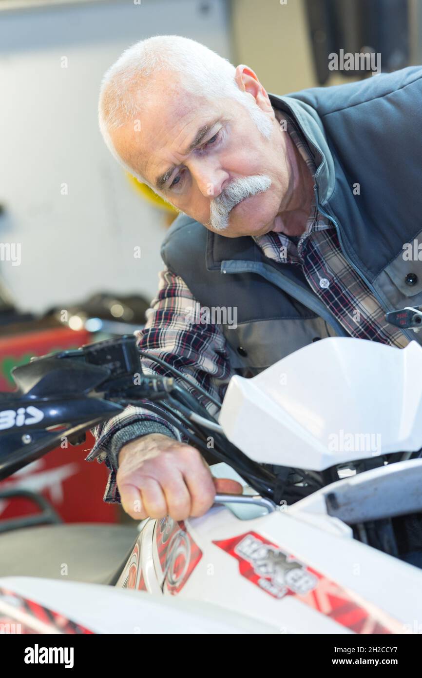 senior motorcycle mechanic fixing a bike Stock Photo - Alamy