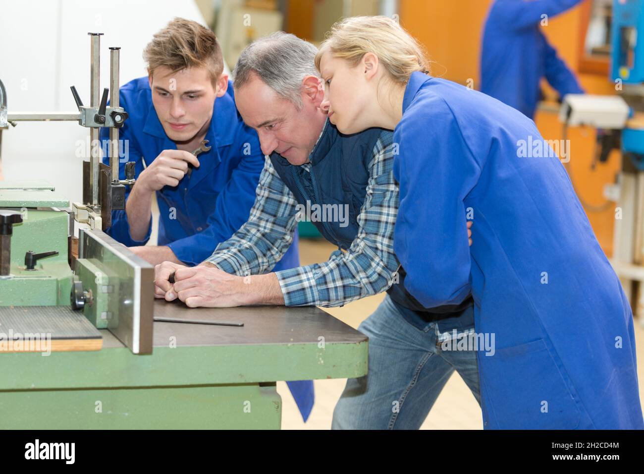 trainees watching senior worker using machinery Stock Photo - Alamy