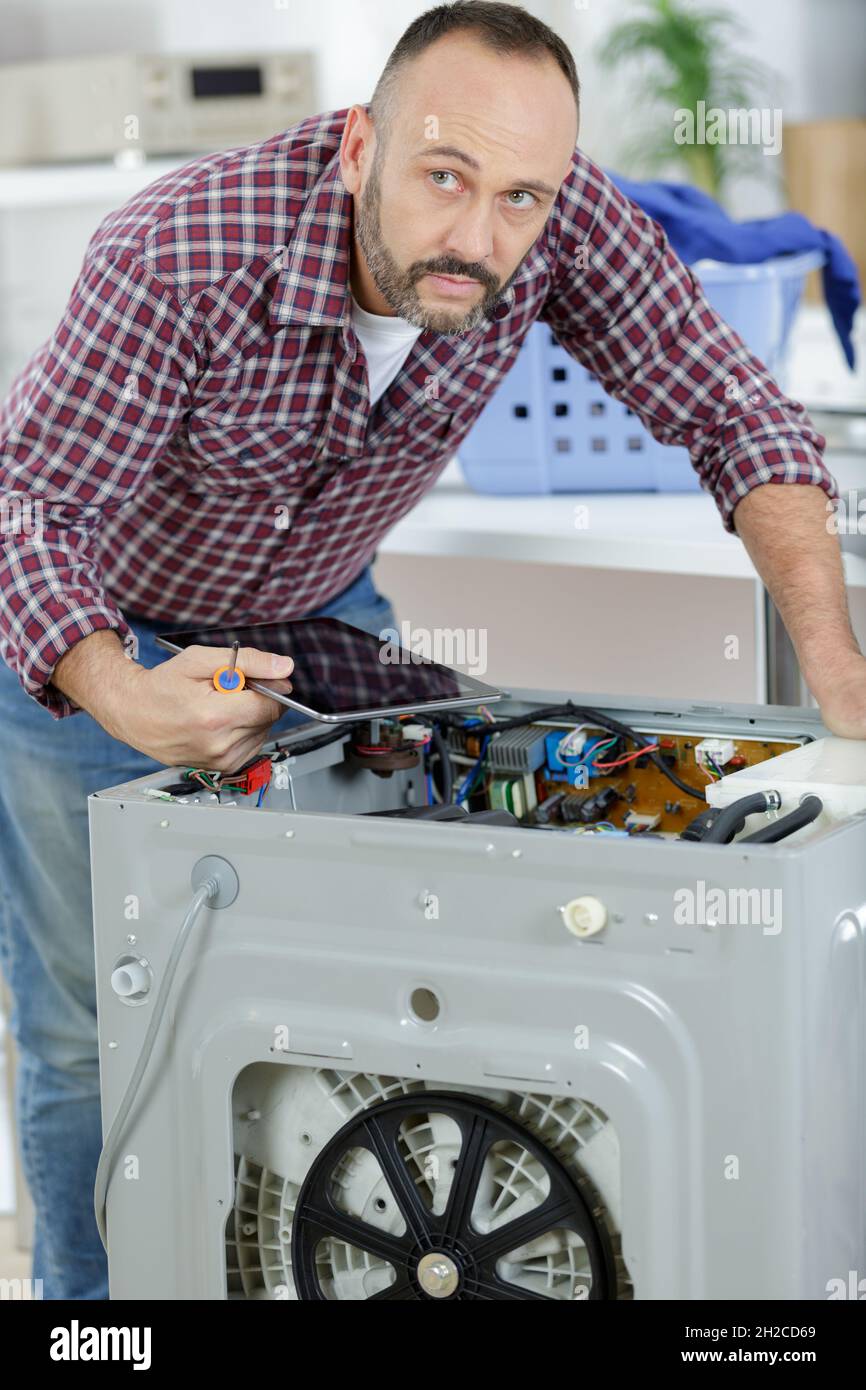 working man plumber repairs washing machine in laundry Stock Photo - Alamy