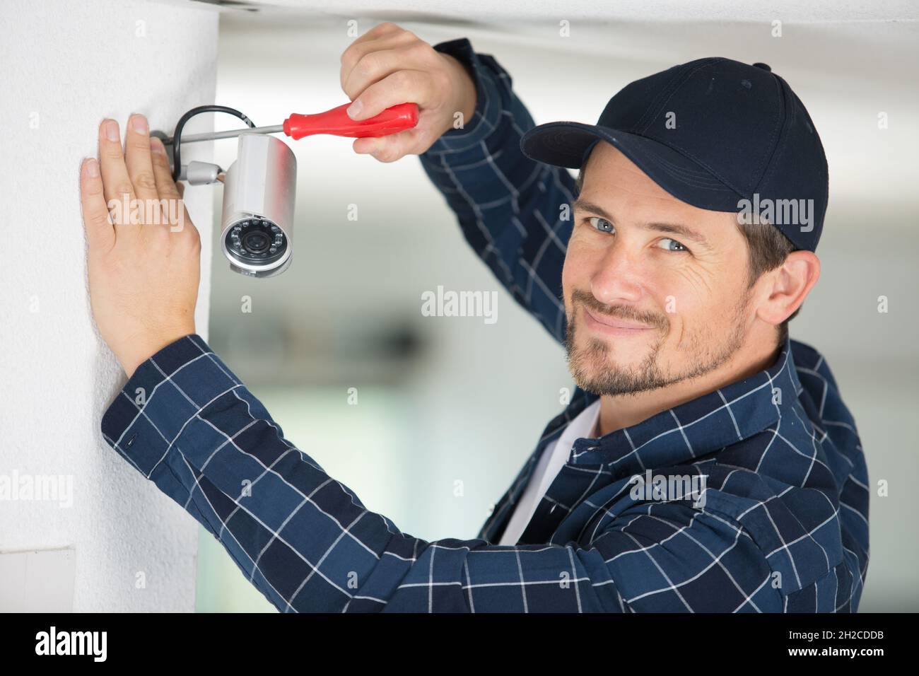 handyman fixing cctv camera to wall Stock Photo - Alamy