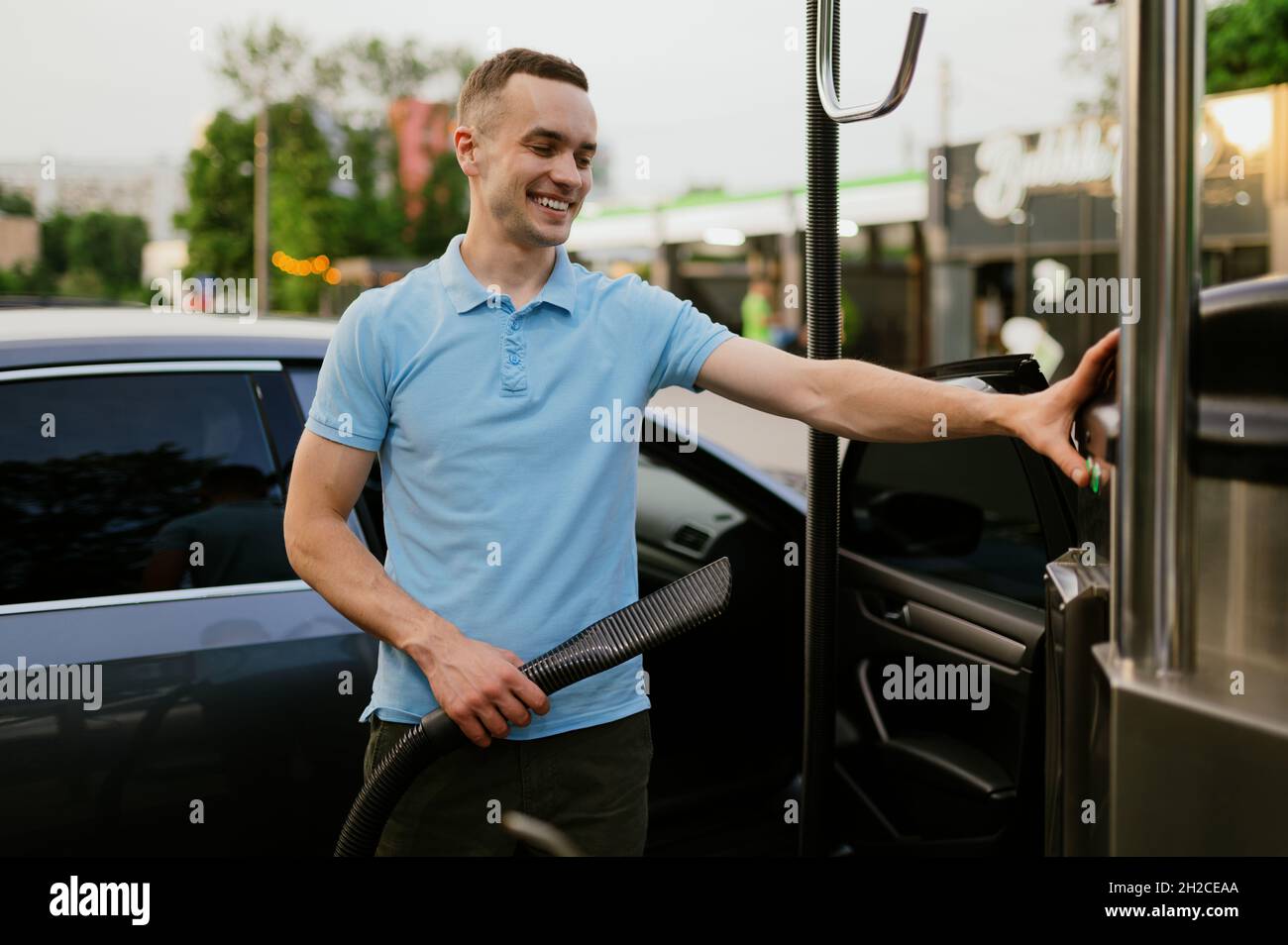 Man using a vacuum cleaner, hand auto wash station Stock Photo - Alamy