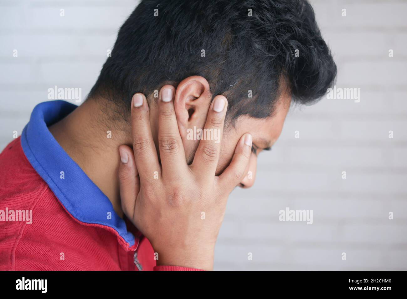 young man having ear pain touching his painful ear Stock Photo - Alamy