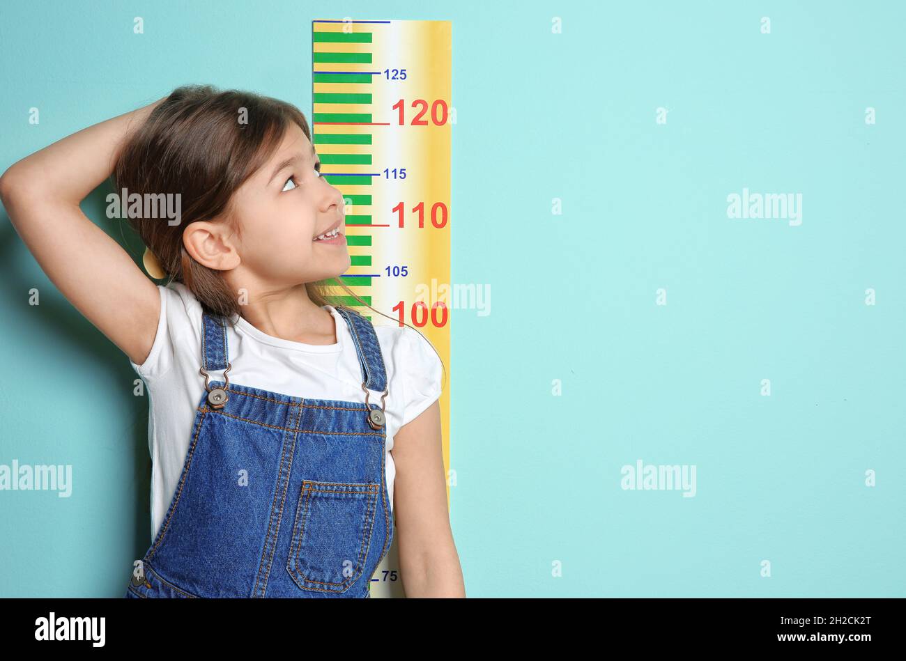 Little girl measuring her height on color background Stock Photo - Alamy