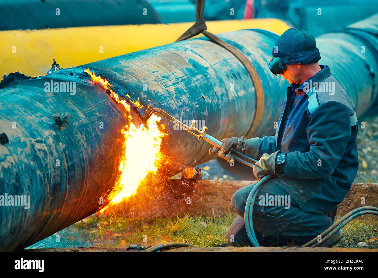 The welder cuts large metal pipes with ocetylene welding. A worker on ...